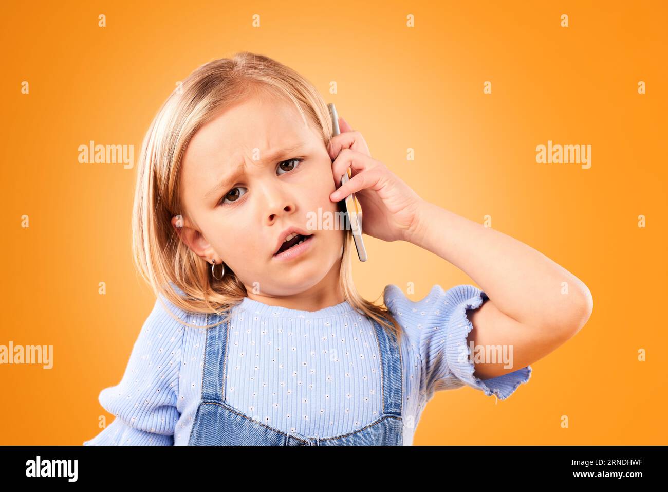 Portrait, phone and a confused girl on an orange background in studio ...