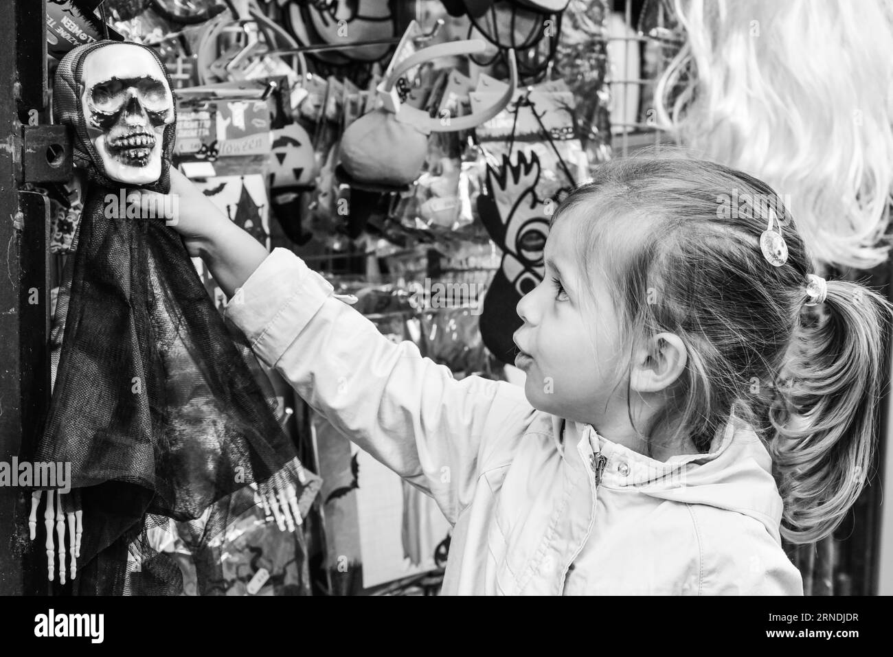 Cute little girl grabbing a skeleton in front of the shop during ...