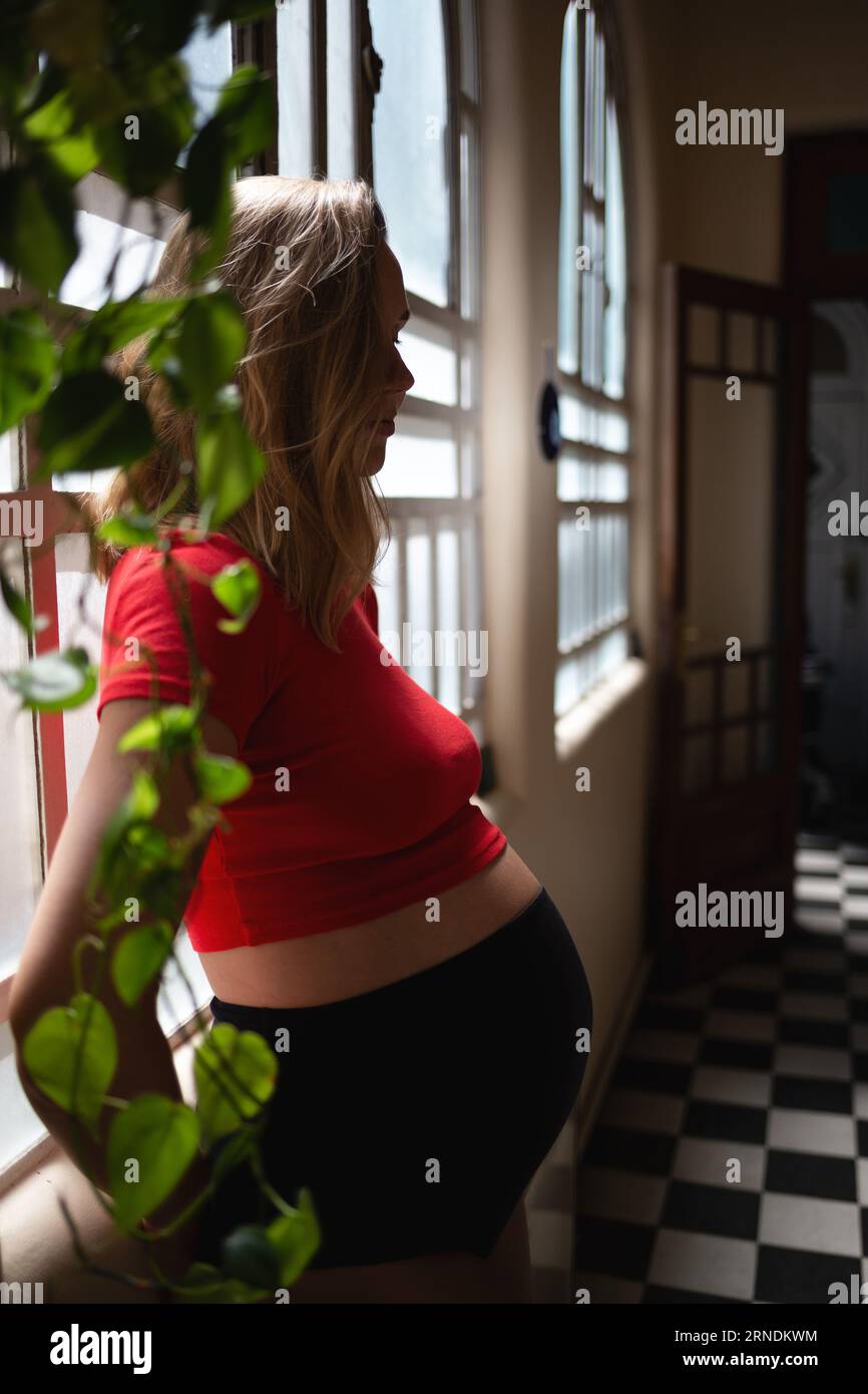 young pregnant woman hugging her big cute tummy while standing by the ...