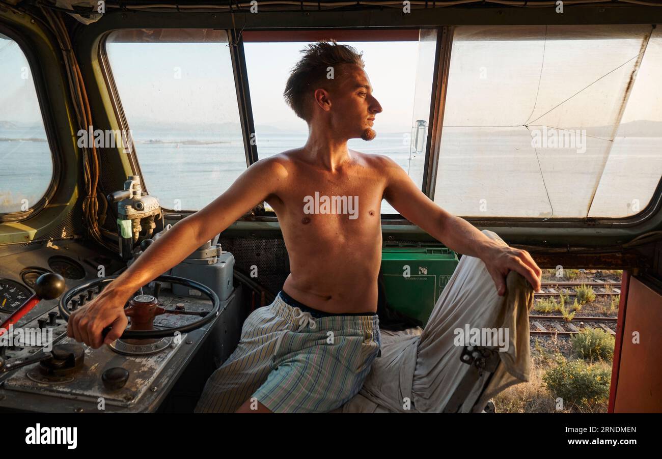 A man Caucasian seated in the driver's cab of a large locomotive ...