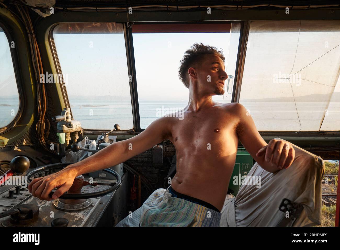 A man Caucasian seated in the driver's cab of a large locomotive ...
