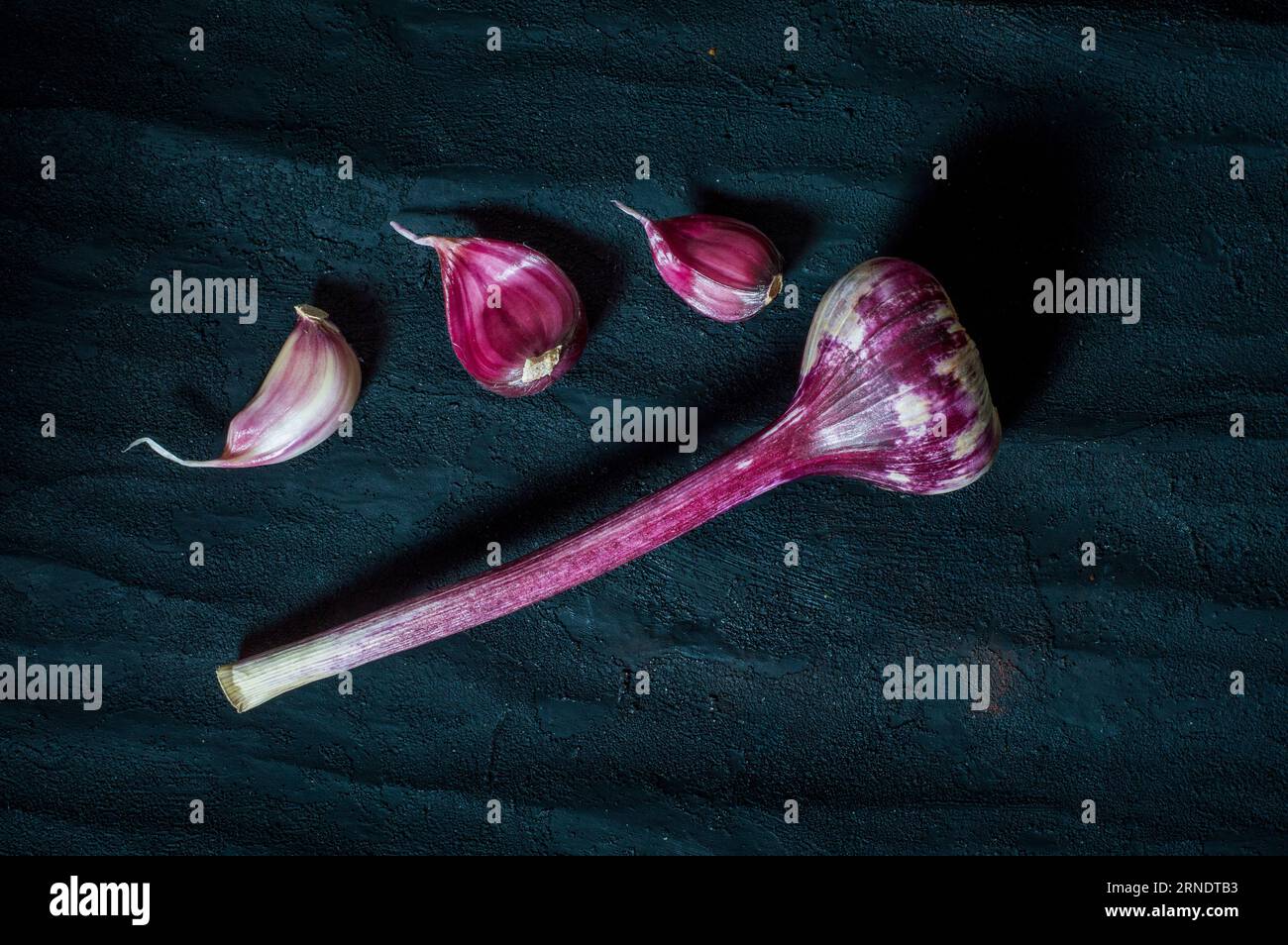 Whole and cloves of purple garlic on a black background, flat lay Stock ...