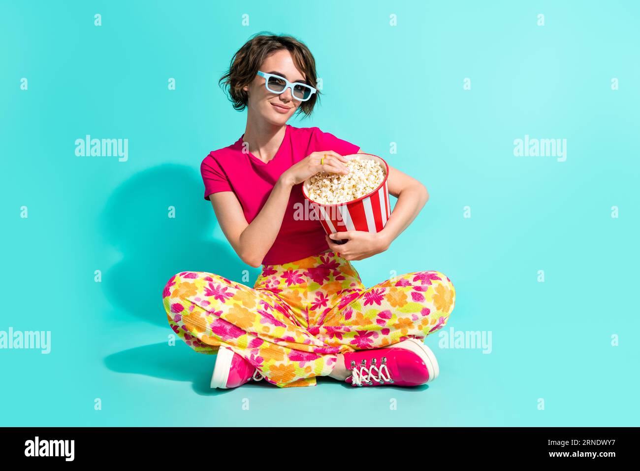 Full length photo of sweet shiny lady flower print pants eating pop ...