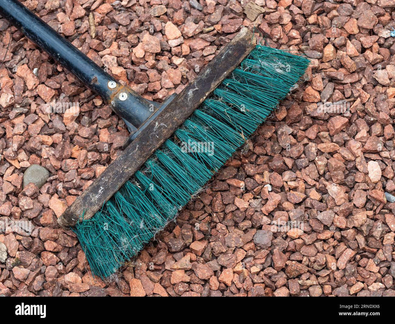 Yard brush closeup of broom head and green bristles lying on a gravel ...
