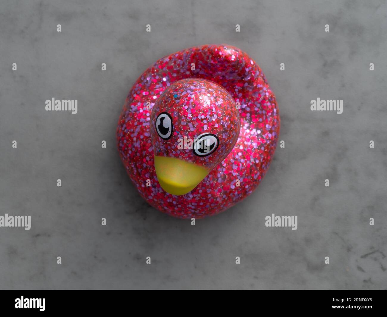 Pink plastic sparkling duck with a yellow beak isolated on a background ...