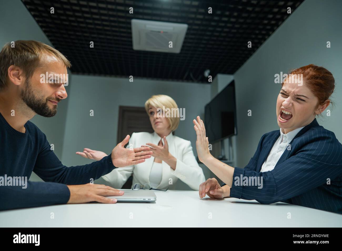 Blond, red-haired woman and bearded man in suits in the office ...