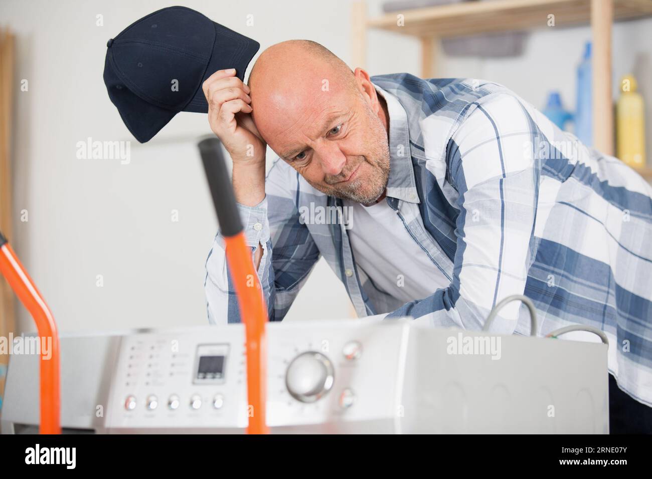 confused delivery man leaning on washing machine Stock Photo - Alamy