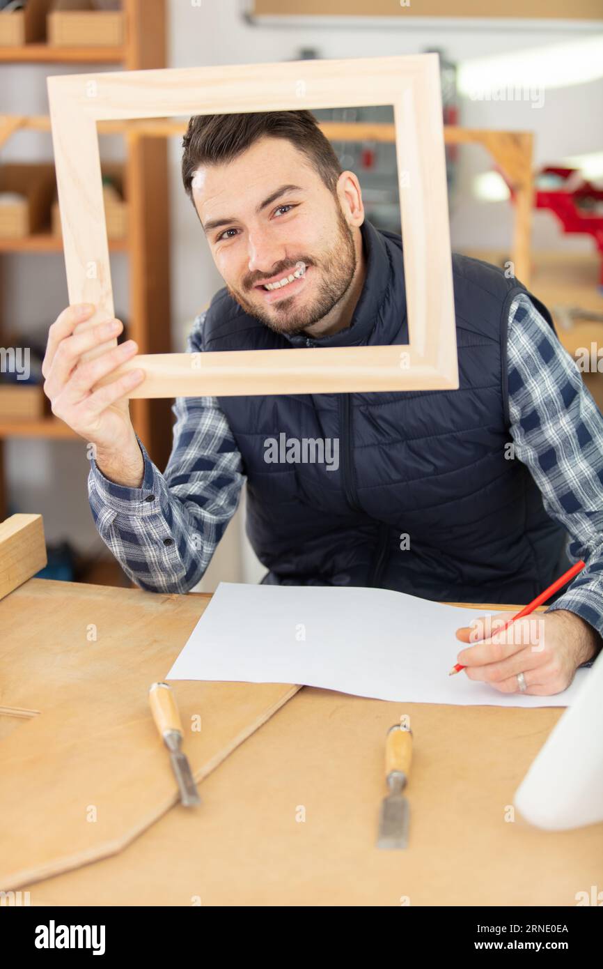 young handsome handyman holding frame Stock Photo - Alamy