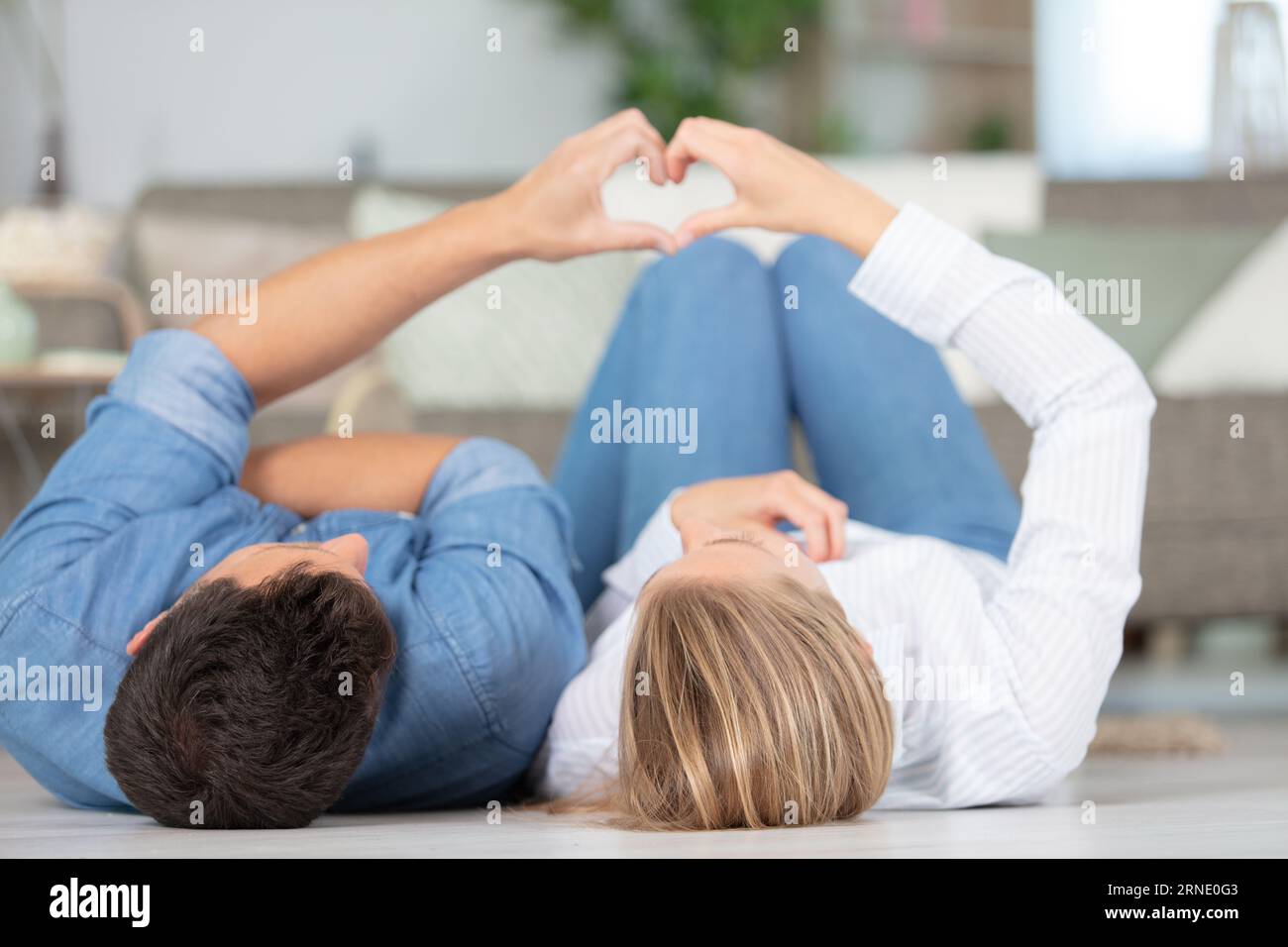 couple laying on the floor making heart sign with hands Stock Photo - Alamy