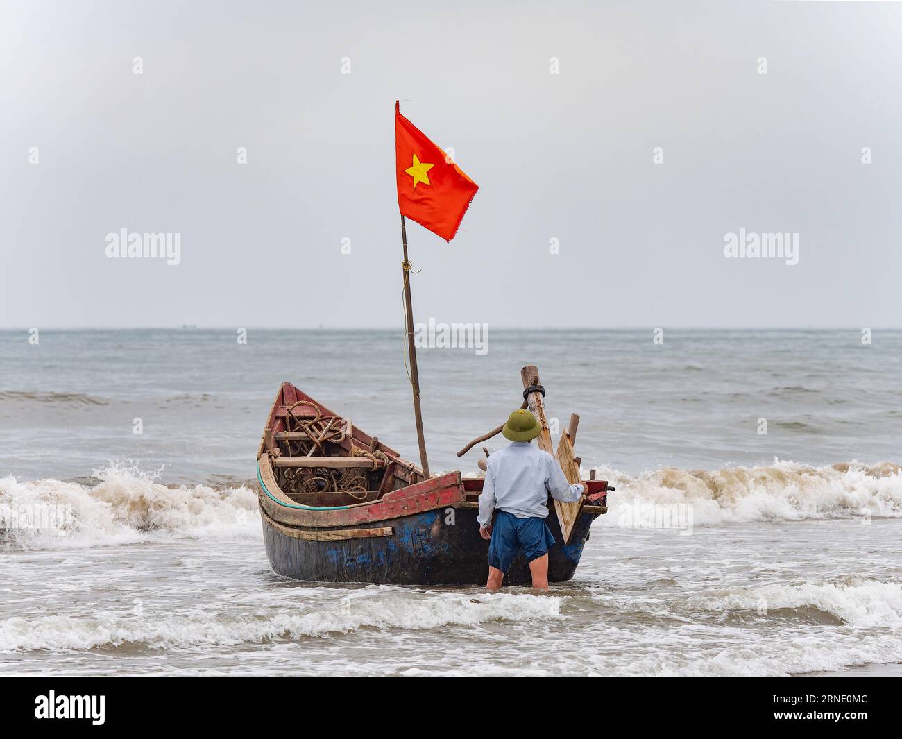 Fisherman launching his boat against wind and high waves in Sam Son ...