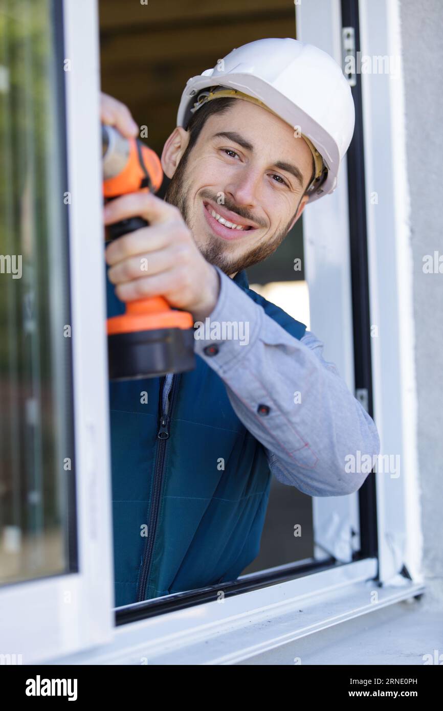 happy man drilling window frame Stock Photo - Alamy