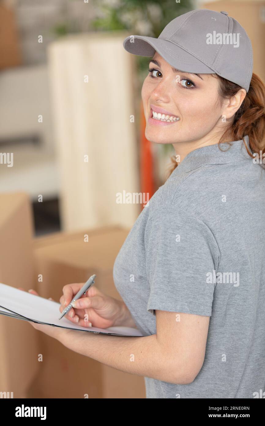 deliverywoman wearing cap holding clipboard smiling Stock Photo - Alamy