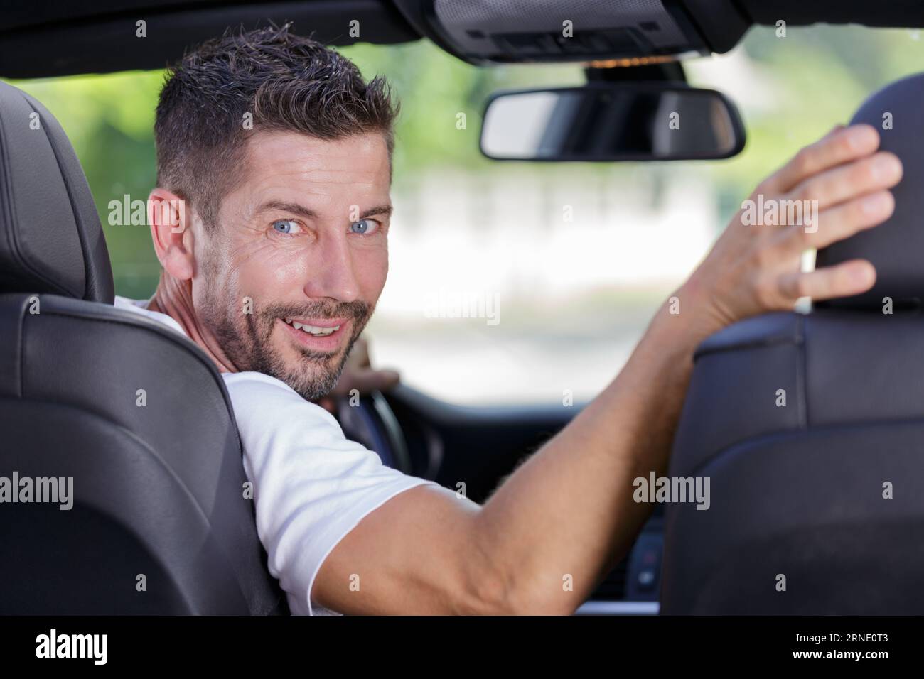 handsome man in new car turning to back of car Stock Photo - Alamy