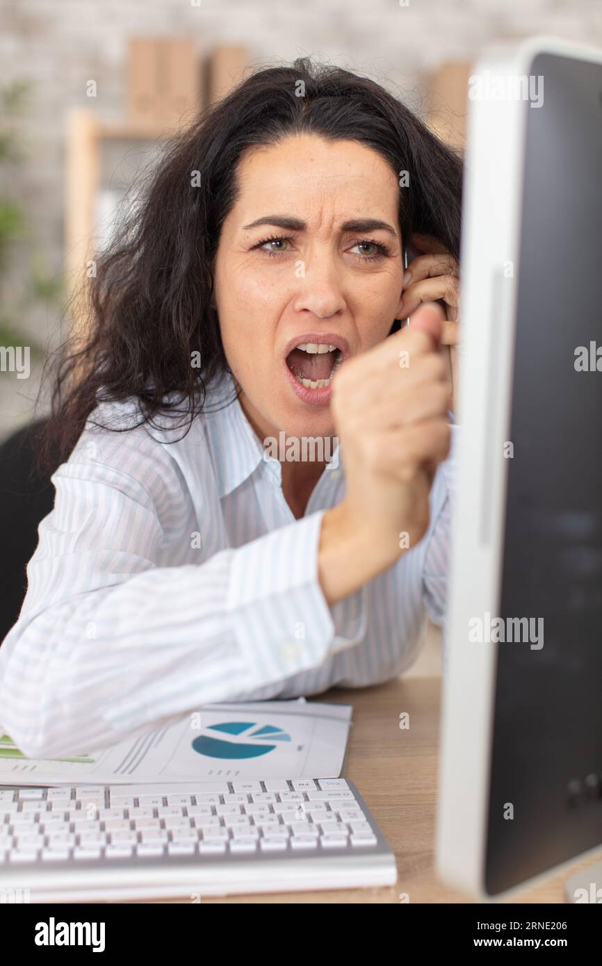 mature angry woman ready to break computer at the office Stock Photo ...
