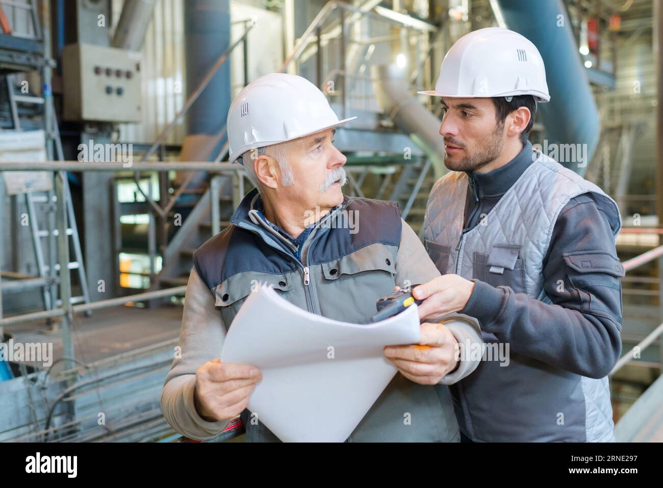 men in factory looking at paperwork Stock Photo - Alamy