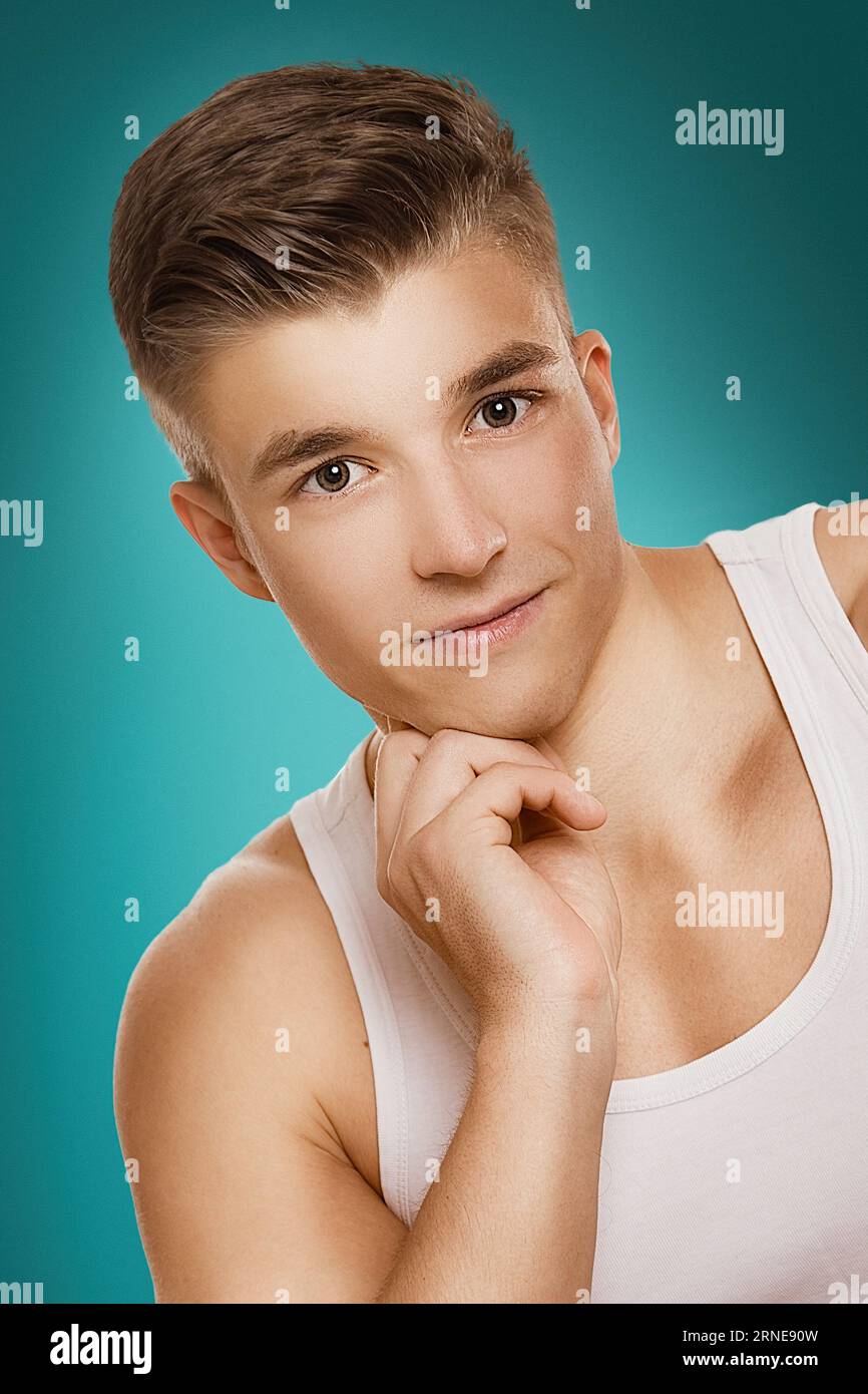 Pretty and handsome male pose in blue studio look at camera with hand ...