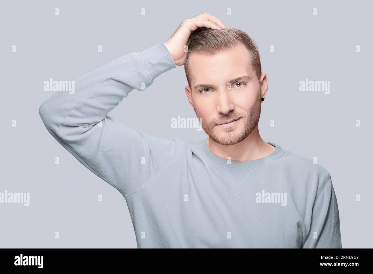 Serious shy guy with hand high on head look straight into camera in hdr ...