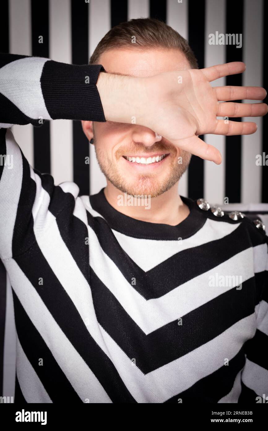 hidden eyes of a young man happily smiling at camera having his hand in ...