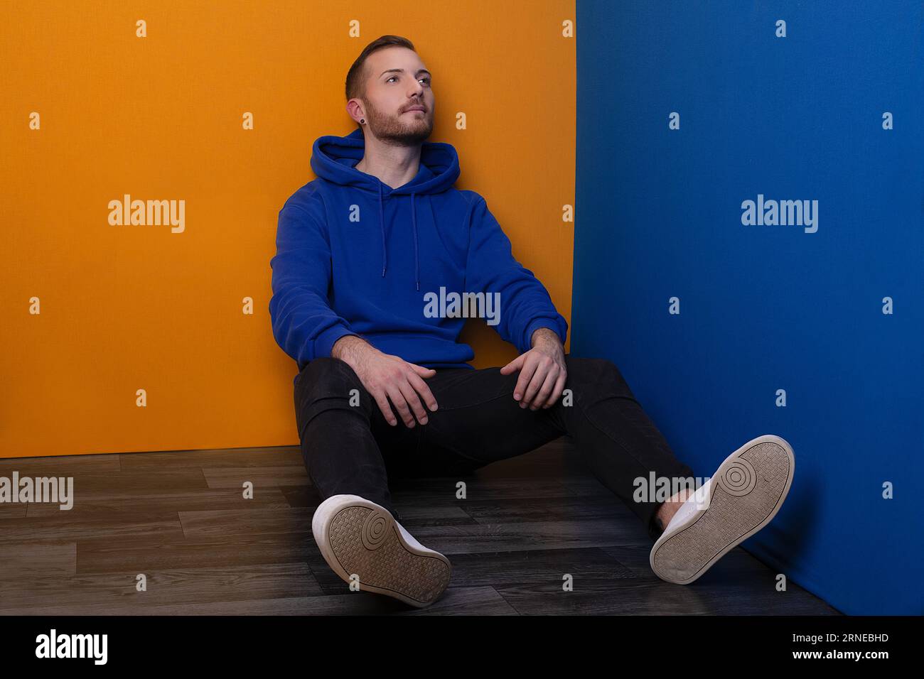 handsome millennial guy stagnates and rest on floor with legs apart and ...