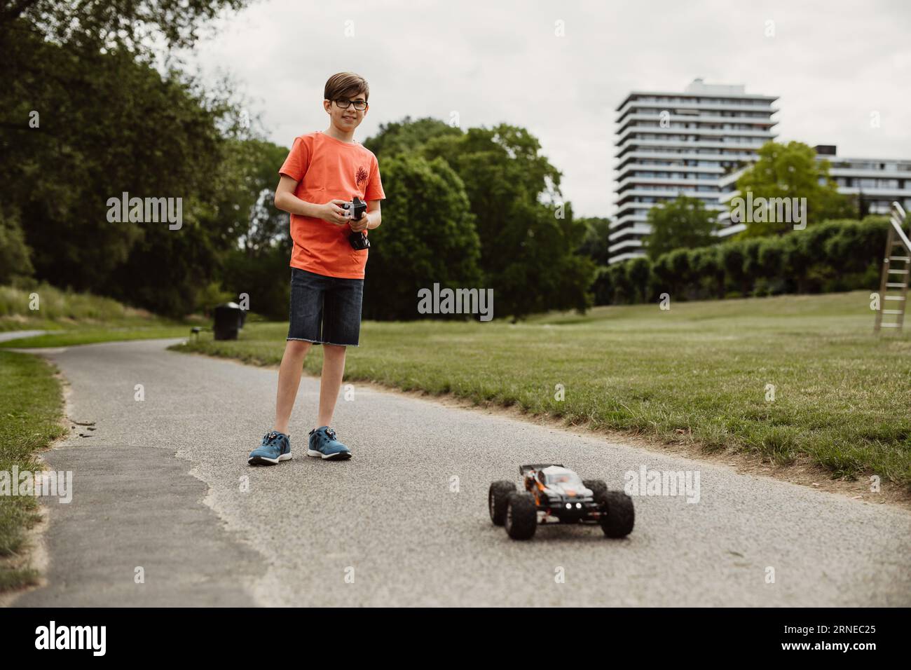 teen boy with electric remote control car toy play outdoor on sidewalk ...