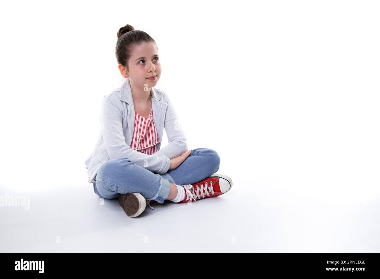 shy child girl sit on floor legs crossed and look up with eyes to top ...
