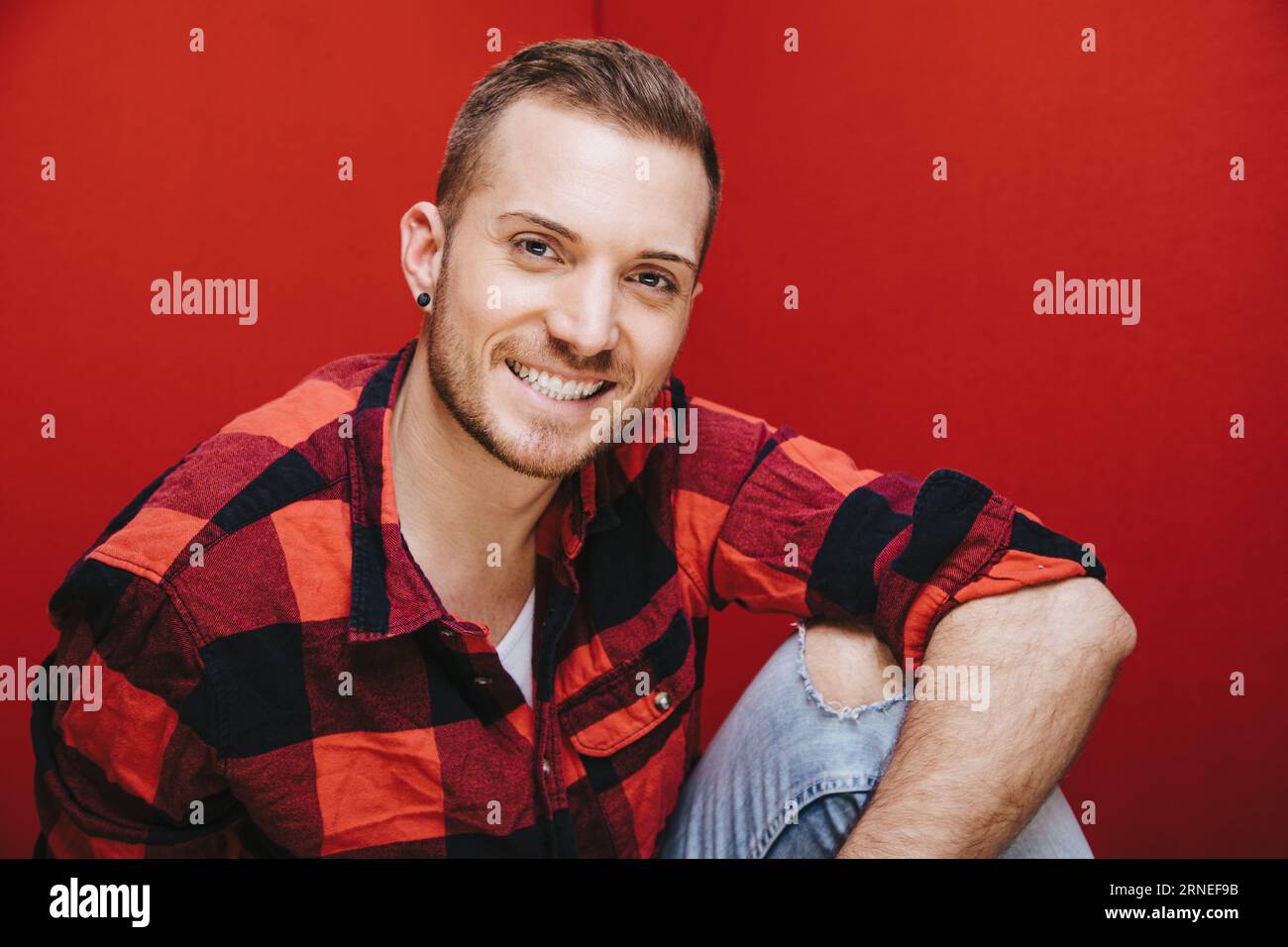 nonchalant guy sit with elbow to knee and arm on his leg while look at ...