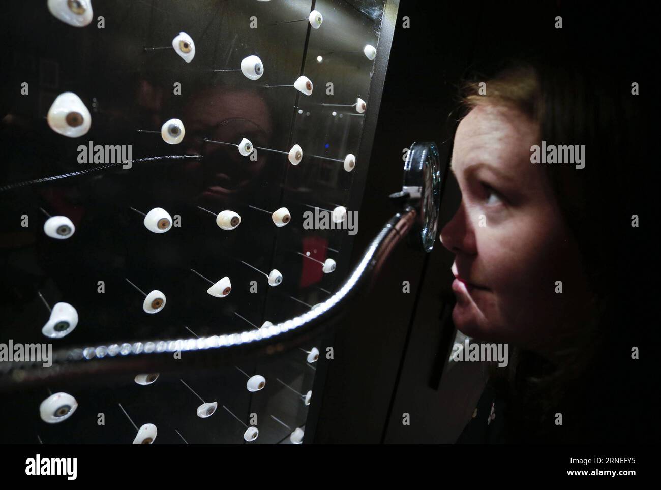 A visitor takes a closer look to some artificial eyes via a magnifier ...