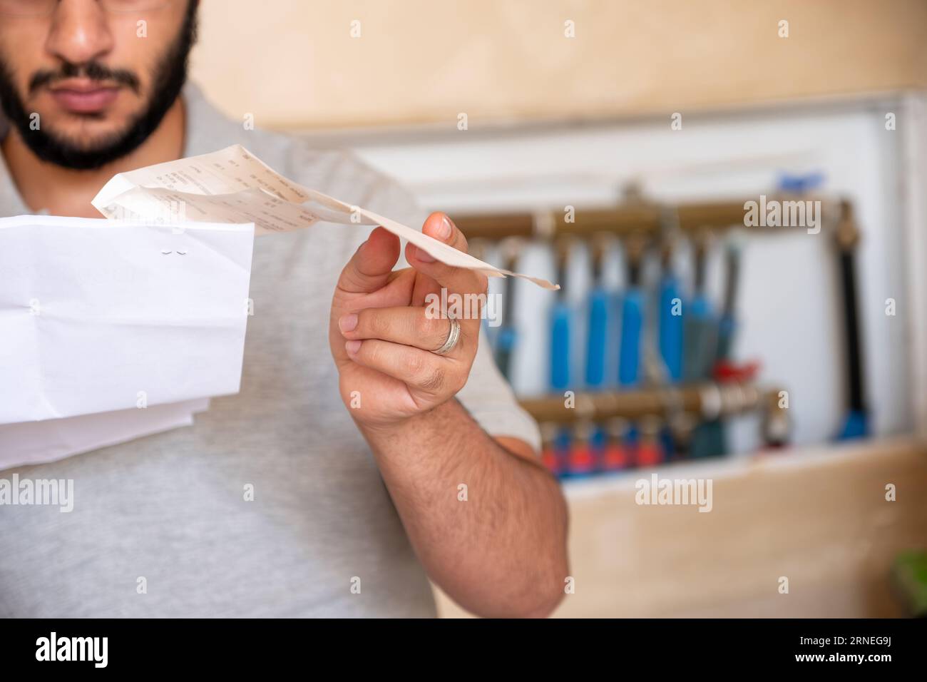 Man holding repair bill with pipes in his background Stock Photo - Alamy