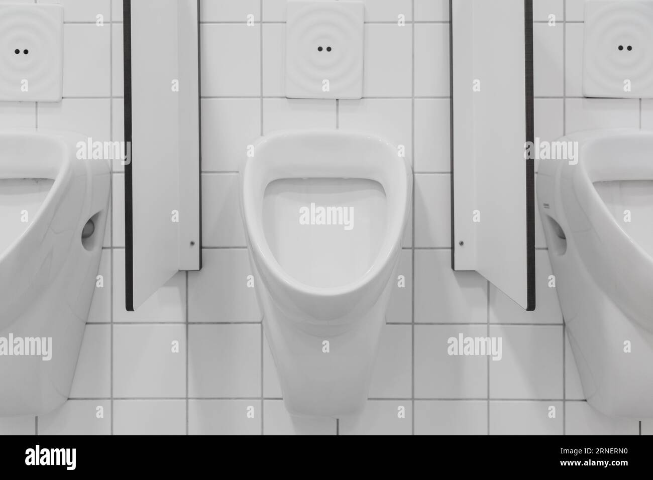 seperated urinals at public restroom with white seperation between and ...