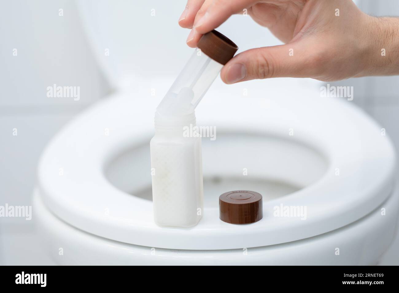 empty plastic jar for stool sample stand on open toilet with human hand ...