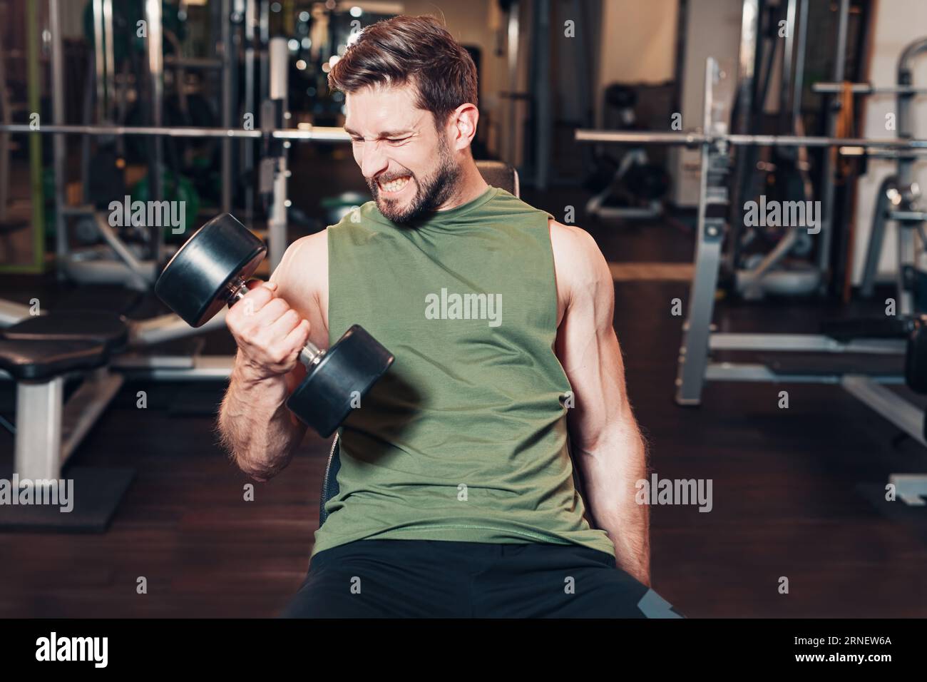 visible pain at face of this sportive man while lifting dumbbells and ...