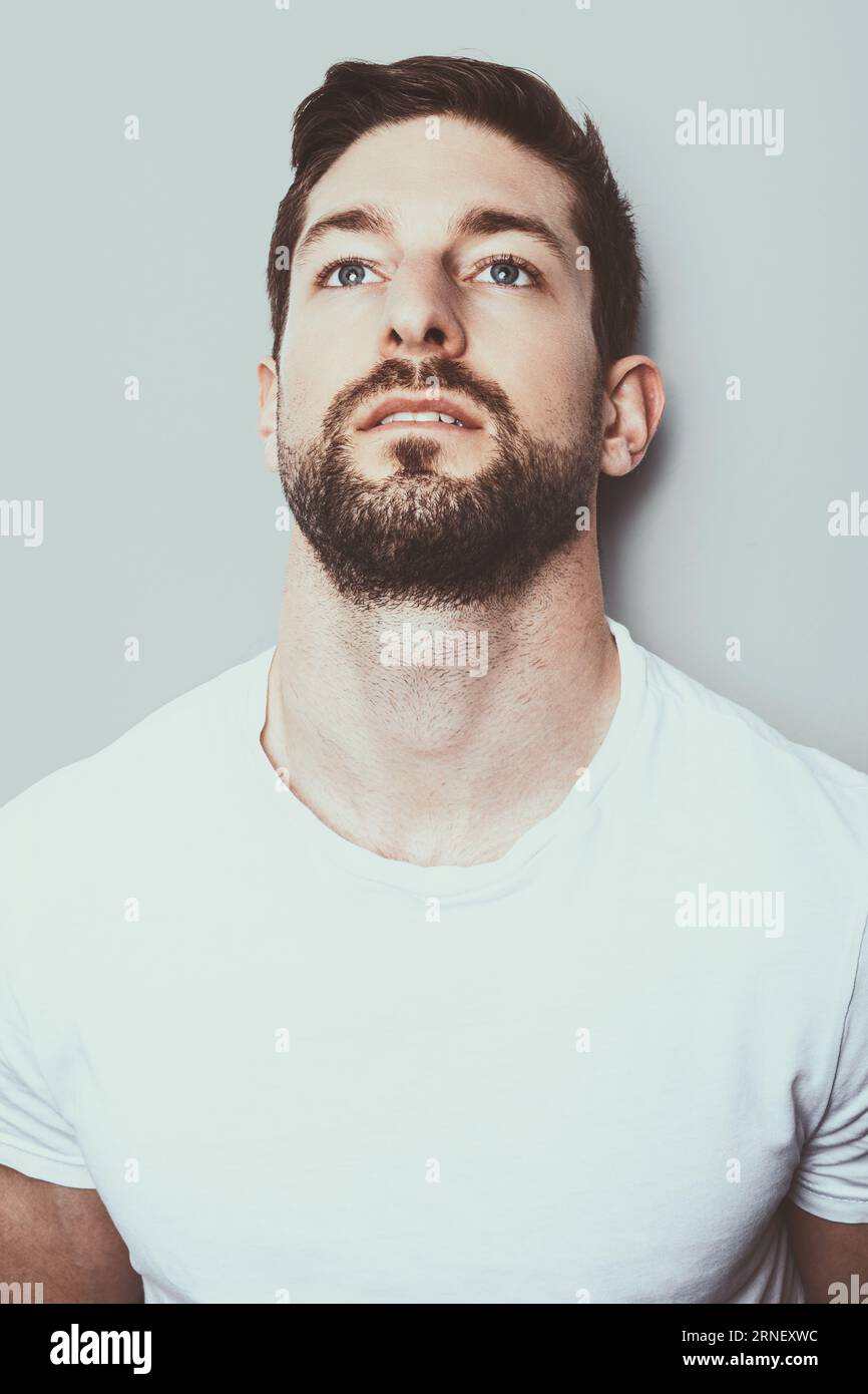 Man in white shirt look up while being in thoughts and think about his ...