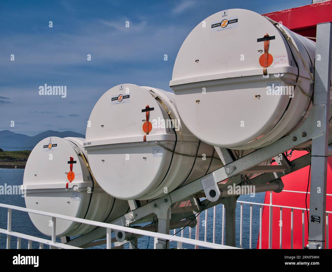 Three white, cylindrical life raft containers in a deployment chute ...