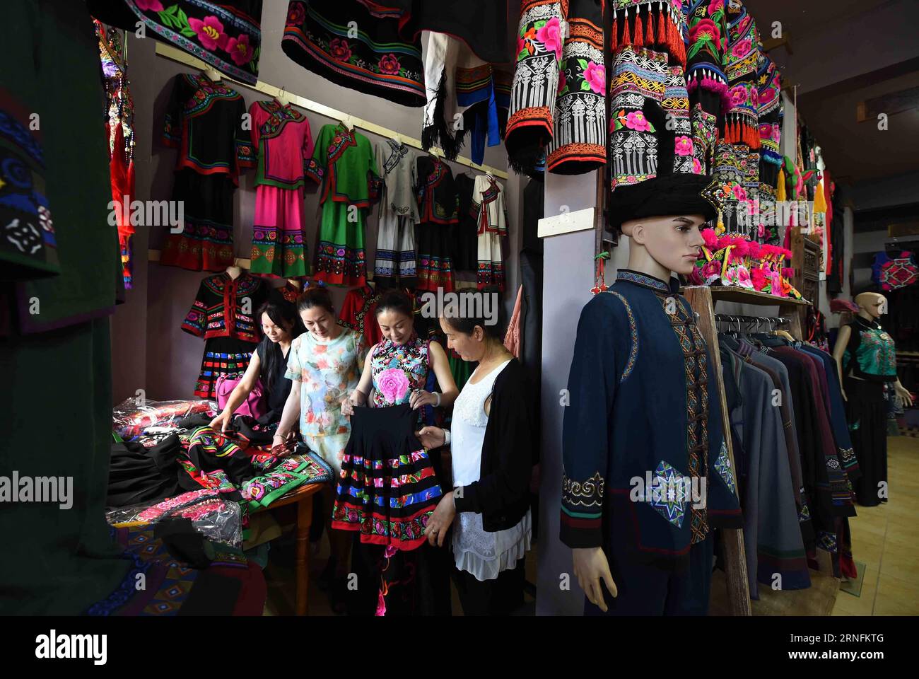 DAYAO, Aug. 14, 2016 -- Luo Jun (2nd R) displays the embroidery ...