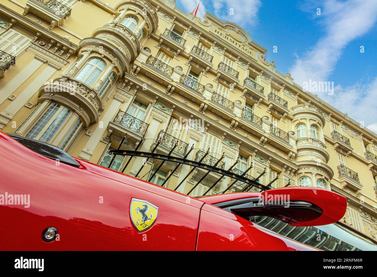 A red Ferrari with yellow prancing horse parked outside Hôtel Hermitage ...