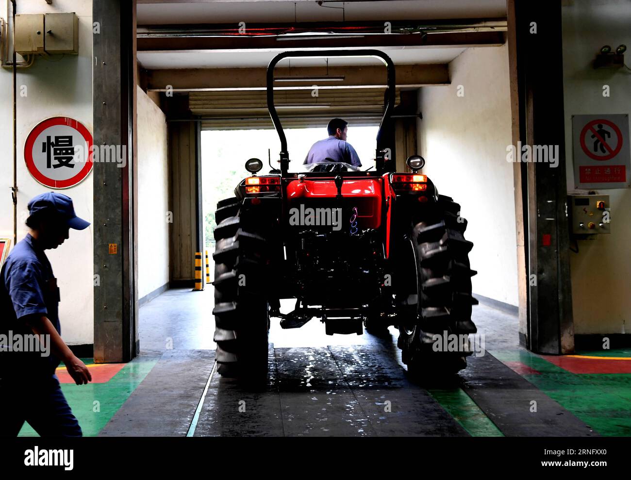 A worker drives a Dongfanghong tractor out of factory in Luoyang ...