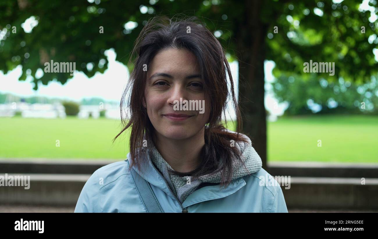 Disheveled carefree woman in 30s standing outside at park scratching ...