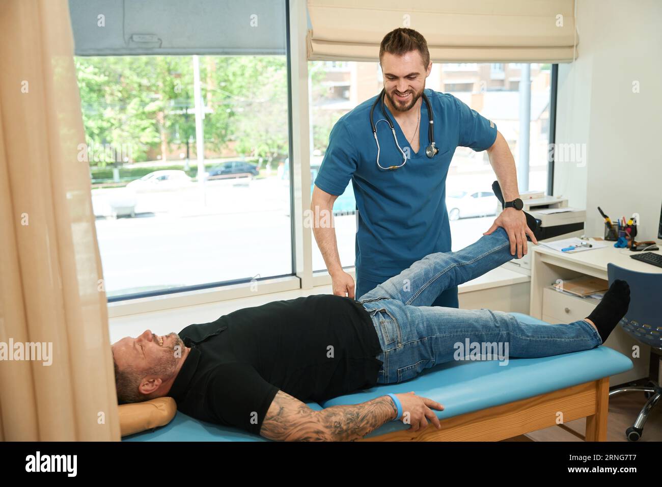 Physiatrist examining patient for sciatica using straight leg raise ...