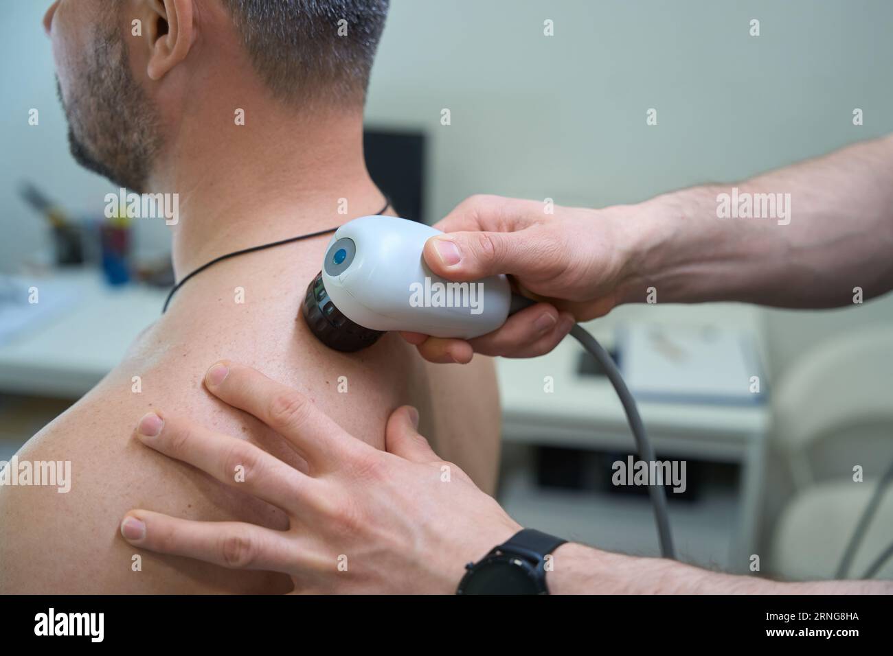 Physiotherapist treating patient for upper back pain with ultrasonic ...