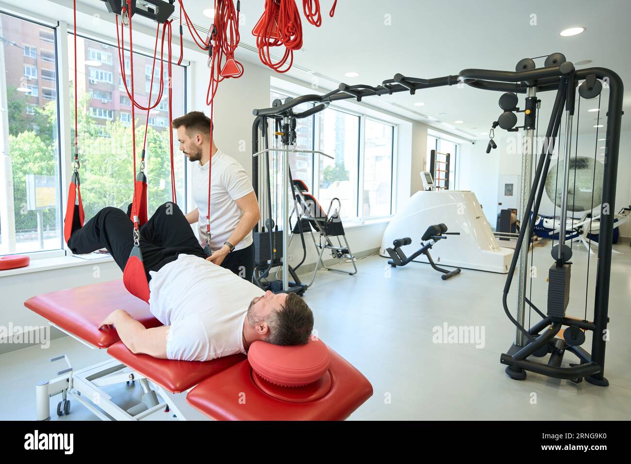 Client doing resistance workout supervised by gym instructor Stock ...