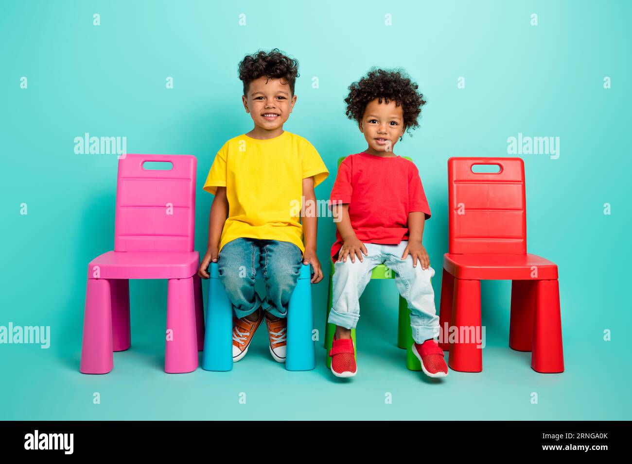 Full body photo of cute two little boys friends sitting chairs dressed ...