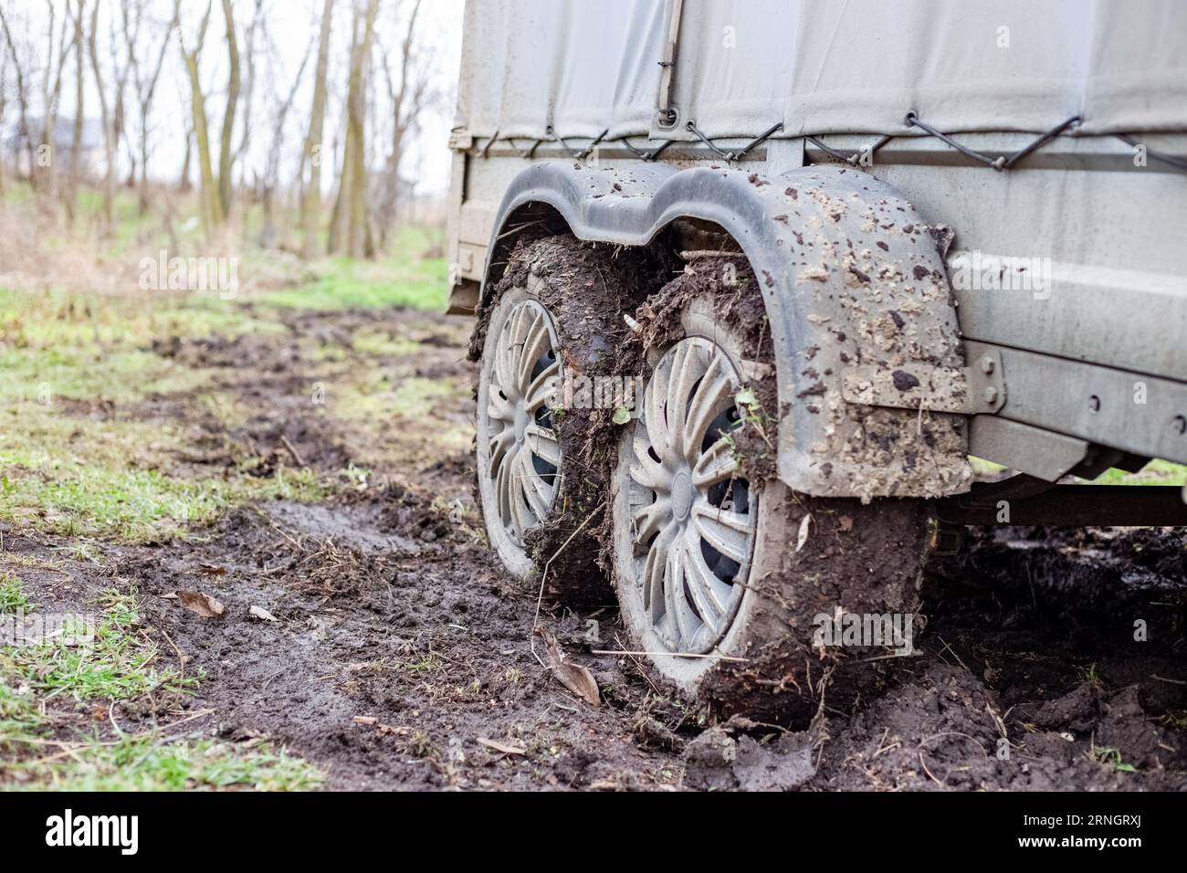 Car two-axle trailer with wheels covered with mud on a muddy road in ...