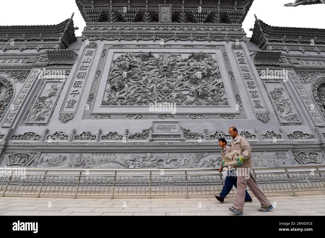 Brick carving artist Shen Zhanwei (R) walks past a brick carving ...