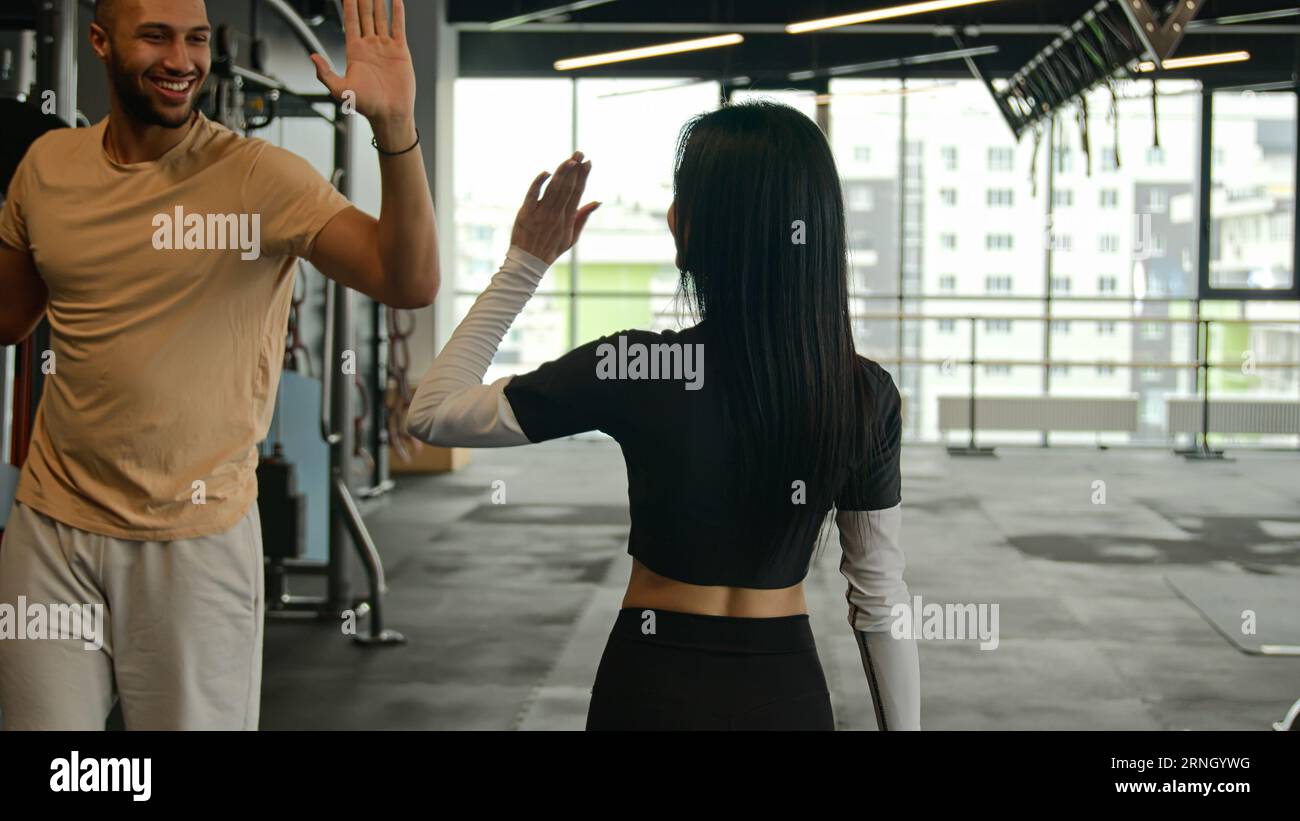 Back view sportswoman fitness trainer go through sport equipment in gym ...