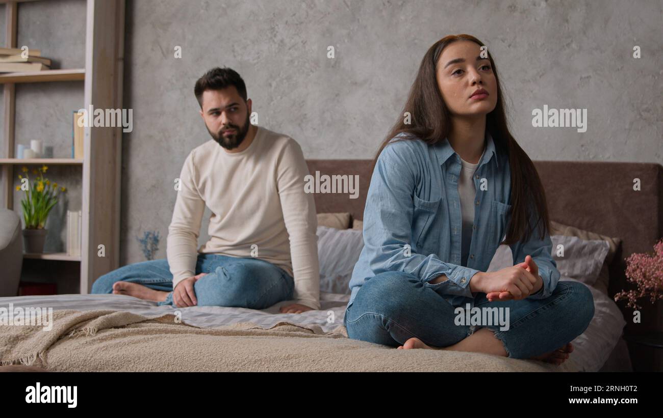 Sad annoyed Caucasian couple family spouses sit apart on bed offended ...