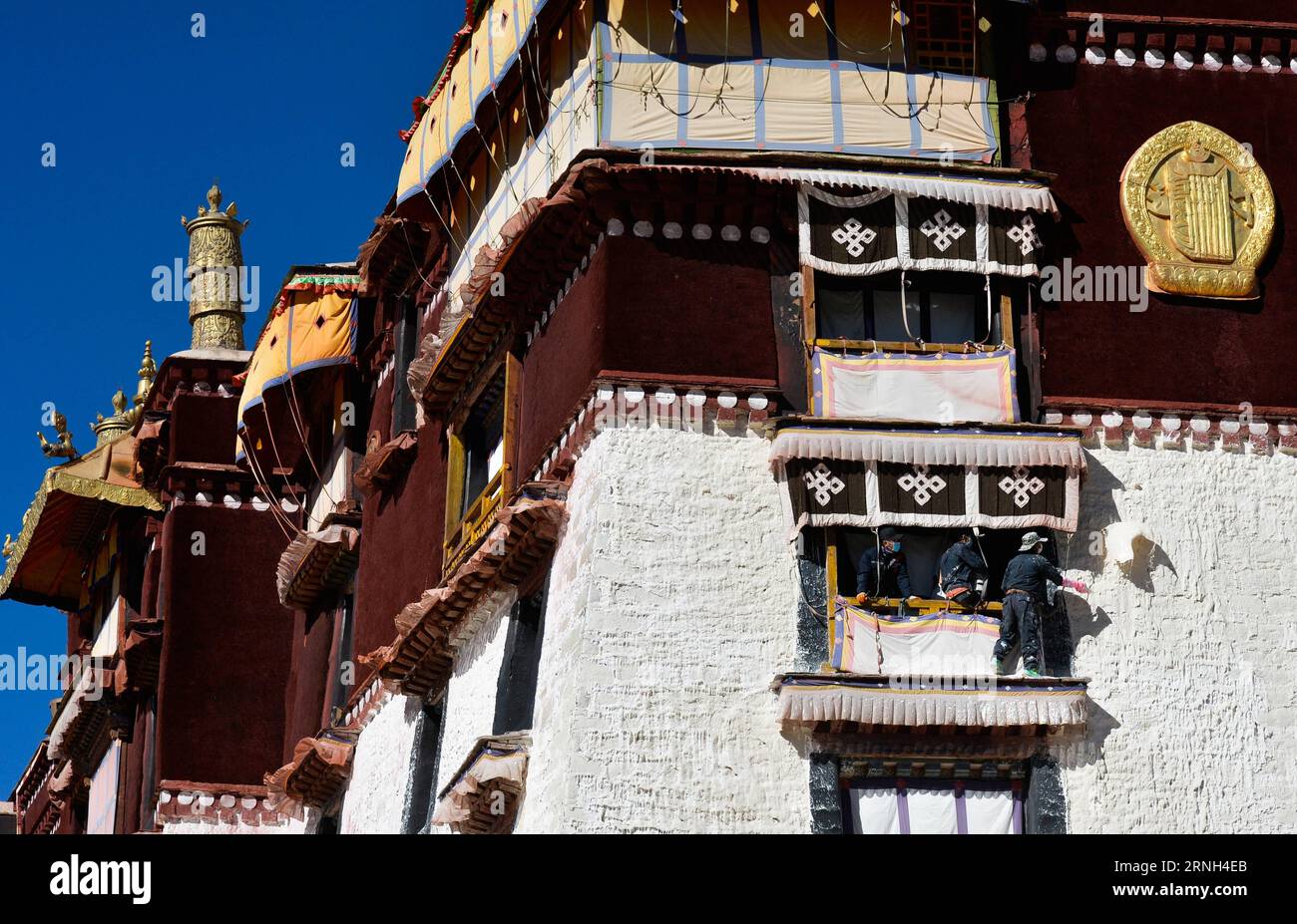 Workers paint the wall of the Potala Palace during an annual renovation ...