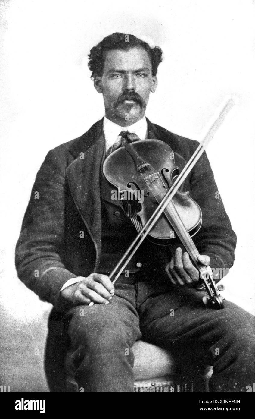A man with a dark-complexion poses for a photograph with his violin in ...