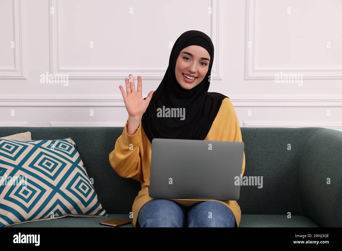 Muslim woman in hijab using laptop on sofa indoors Stock Photo - Alamy