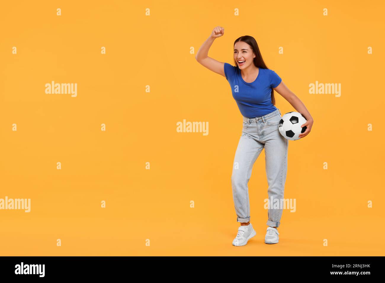 Happy fan with soccer ball celebrating on yellow background, space for ...