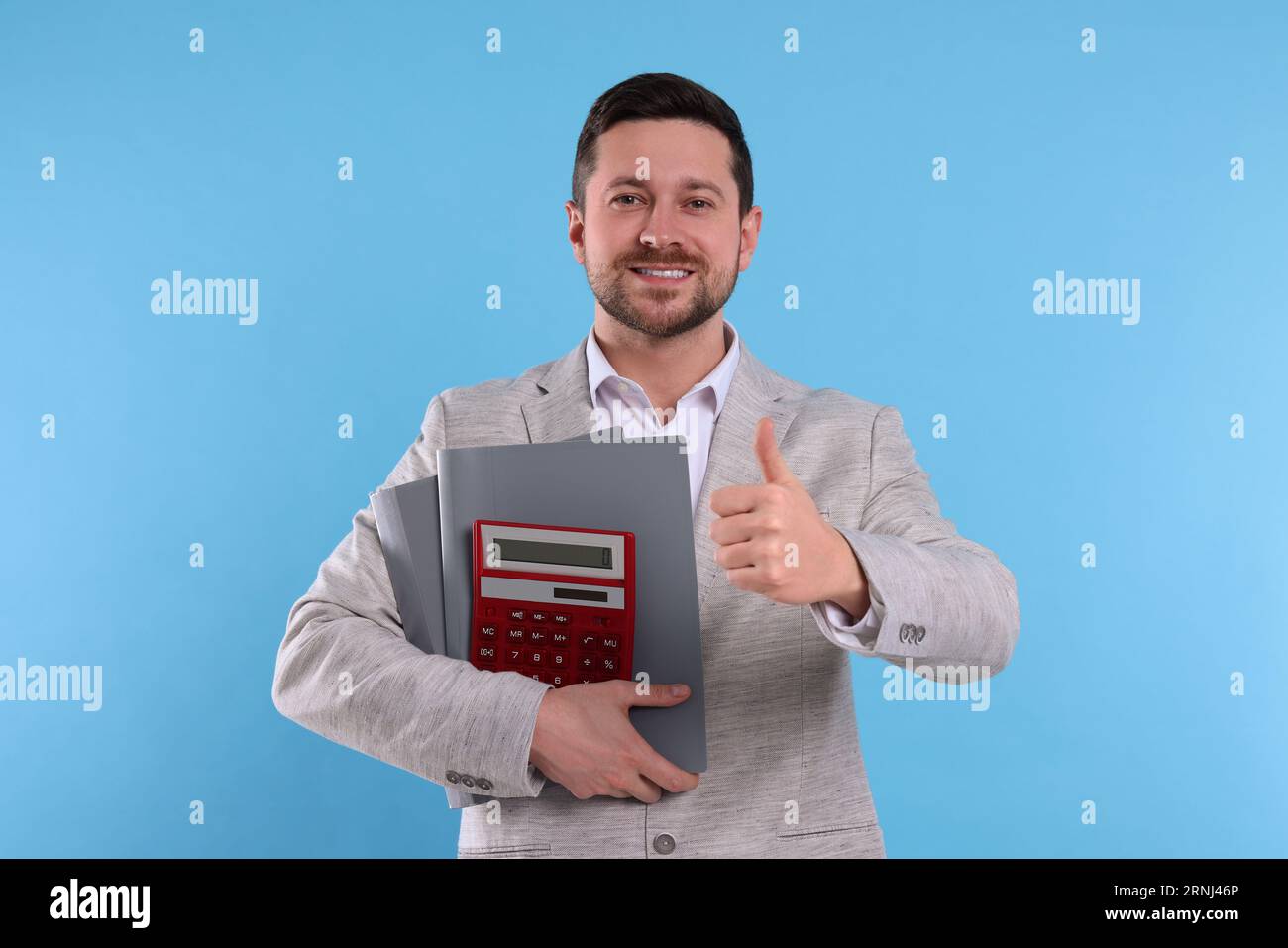 Happy accountant with calculator and folders showing thumb up on light ...
